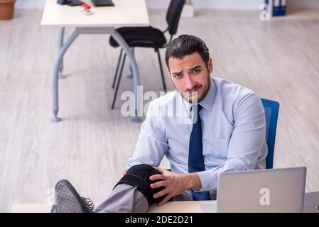 Young leg injured employee working in the office Stock Photo - Alamy