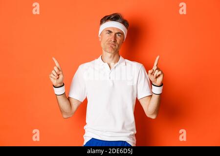 Portrait of skeptical adult sportsman in headband and t-shirt ...