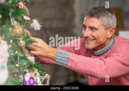 happy man decorating christmas tree at home Stock Photo - Alamy