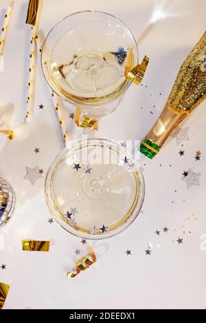 Champagne bottle with confetti, glasses and christmas decor on colored ...