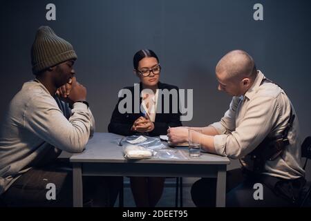 A black drug addict is interrogated at a police station by an ...