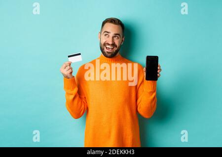 Online shopping. Thoughtful man shop in internet, showing mobile screen ...