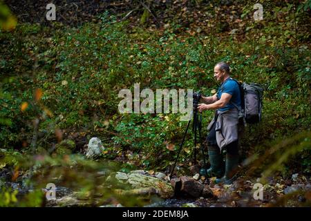 Professional nature photographe with large backpack, camera and tripod ...