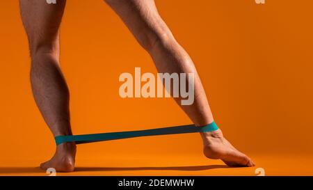Muscular men's legs with elastic band for fitness, do exercises to ...