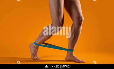 Muscular men's legs with elastic band for fitness, do exercises to ...