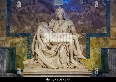 A PIETA STATUE OF MARY MOTHER HOLDING DEAD BODY OF JESUS CHRIST IN HER LAP WITH WHITE LILIES ...
