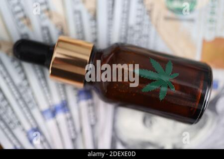 Bottle of marijuana extract lying on large sum of dollars closeup Stock ...