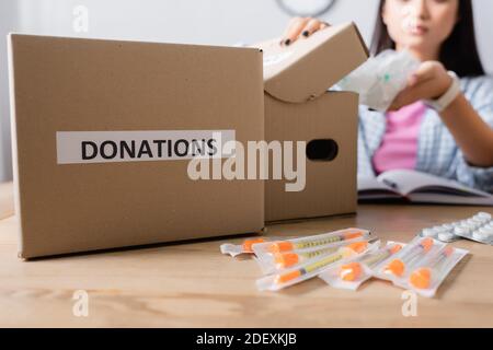 Cropped view of pills and carton box with donations lettering in hands ...