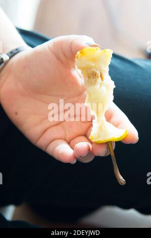 A vertical shot of a hand holding a bitten donut with green frosting on ...
