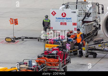 Aircraft ramp loader loading baggage to conveyor belt on airport apron ...
