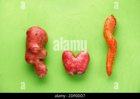 Ugly funny vegetables, lumpy potatoes and a twisted carrot on a green ...