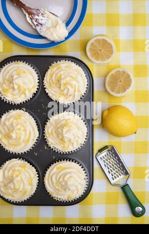 Top view of a sponge lemon cake on a table next to other plates with ...