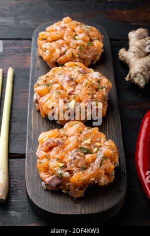 Raw fish patties with salmon fillet and lemongrass, on black wooden ...