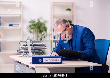 Aged businessman clown working in the office Stock Photo - Alamy