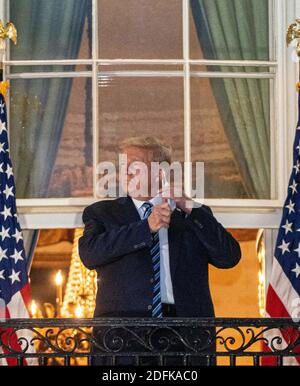 President Donald Trump removes his mask as he stands on the Blue Room ...