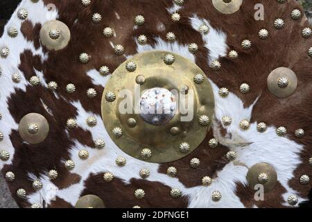 A round Viking style shield, with a metal boss, painted in a yellow and ...