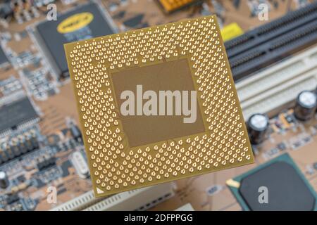 Gold pinouts on underside of a desktop AMD CPU with motherboard. This ...
