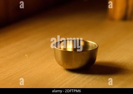Golden brass singing bowl on a wooden table in dramatic light Stock ...