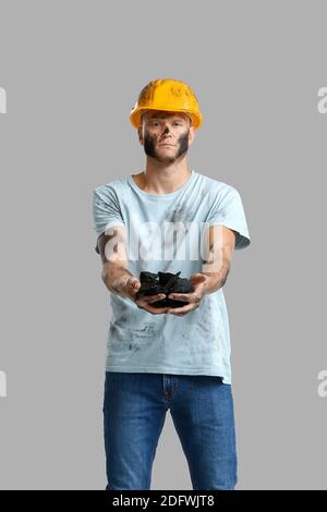 Miner man with coal on grey background Stock Photo - Alamy