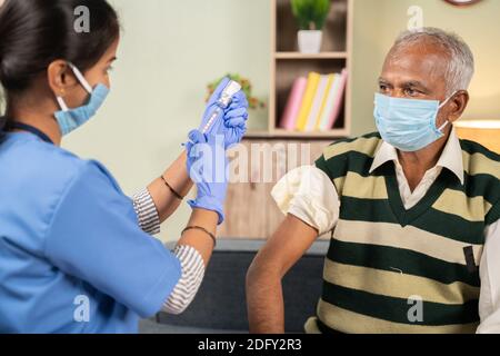 Doctor preparing vaccination shot to elderly patient by holding syringe ...