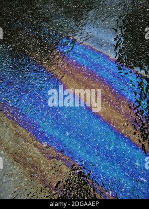 A closeup vertical shot of colorful gasoline fuel stain on asphalt ...