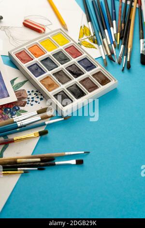 Artists wooden table with paints and colored paper Stock Photo - Alamy