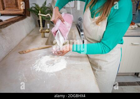 oman in a traditional vintage kitchen making a dough to make a homemade ...