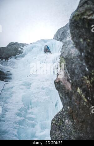 An ice climber climbs up a steep gully full of ice in Maine alpine ...