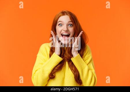 Impressed and surprised european ginger girl in red warm sweater open ...