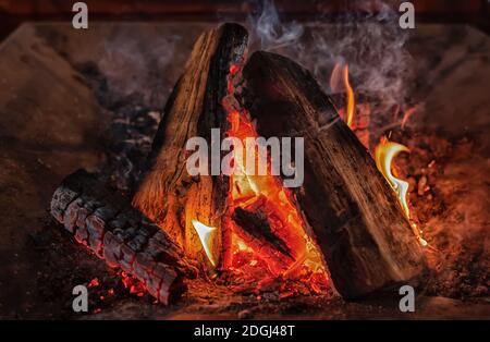 Close-up view of glowing coals and burning firewood inside an old stove ...