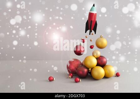 Toy rocket launching with red and gold christmas baubles representing ...
