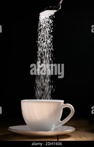 White granulated sugar pouring into a white cup Stock Photo - Alamy