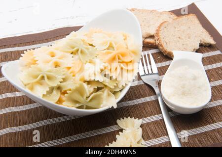 Appetizing farfalle pasta served in white bowl, garnished with parmesan ...