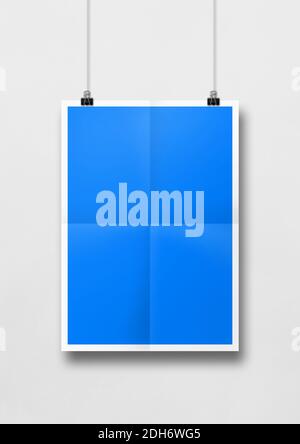 Blue folded poster hanging on a concrete wall with clips. Blank mockup ...