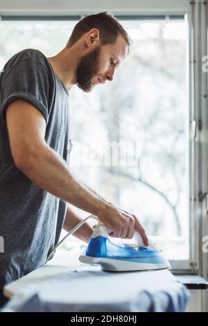 Side view of man ironing shirt Stock Photo - Alamy