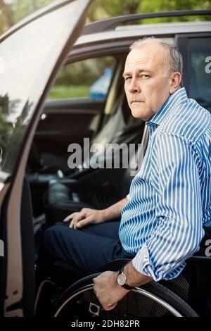 Side portrait of man sitting at outside restaurant with drink working ...