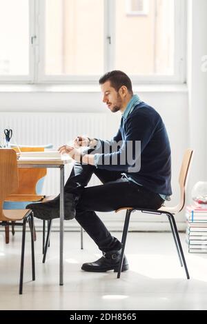 full length view of businessman in formal wear holding laptop near ...
