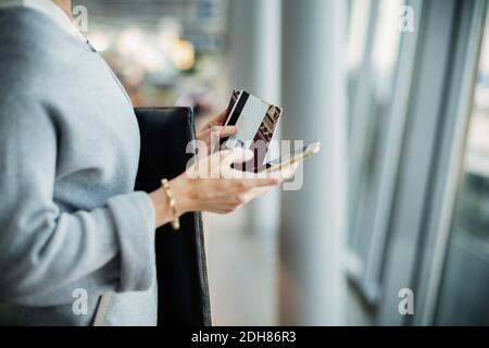 Midsection of businesswoman using smart phone at airport lobby Stock ...