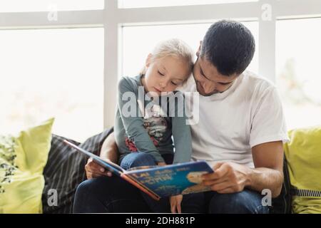 Male Teacher Reading Story To Group Of Elementary Pupils Wearing ...