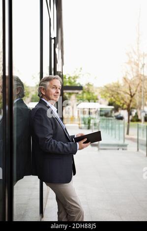 Senior business man studio standing isolated on gray wall holding ...