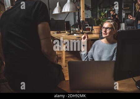 Rear view of young female programmer sitting at her workplace in front ...