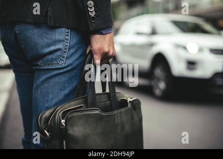 Midsection of businessman carrying briefcase by car Stock Photo - Alamy