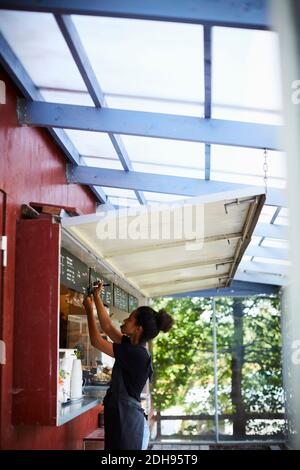 African american waitress holding menu near blurred client in outdoor ...