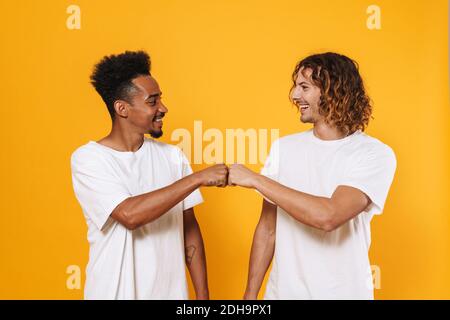 Happy multicultural two guys smiling and fist bumping isolated over ...