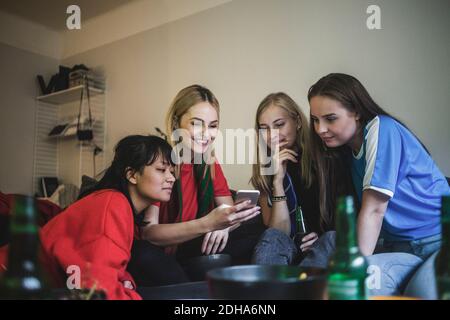 Smiling female friends using mobile phone Stock Photo - Alamy