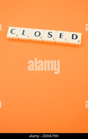A vertical shot of the word "Closed" made of tiles on orange background ...