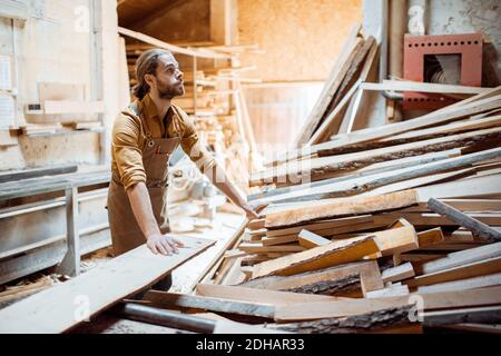 Carpenter or warehouse worker choosing raw wood material for the work ...