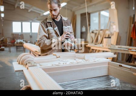 Carpenter grinding joinery product with carvings, finishing woodwork at ...