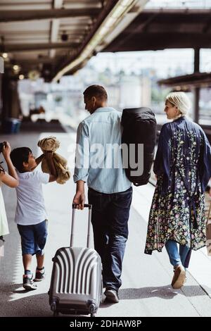 Rear view of family with suitcase while walking in airport or hotel ...