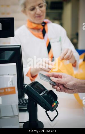 Cropped view of customer paying with credit card near blurred ...